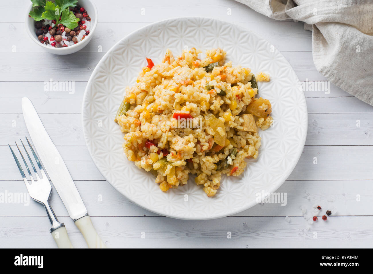 Pilaf with vegetables and chicken in a gray plate on a light background ...