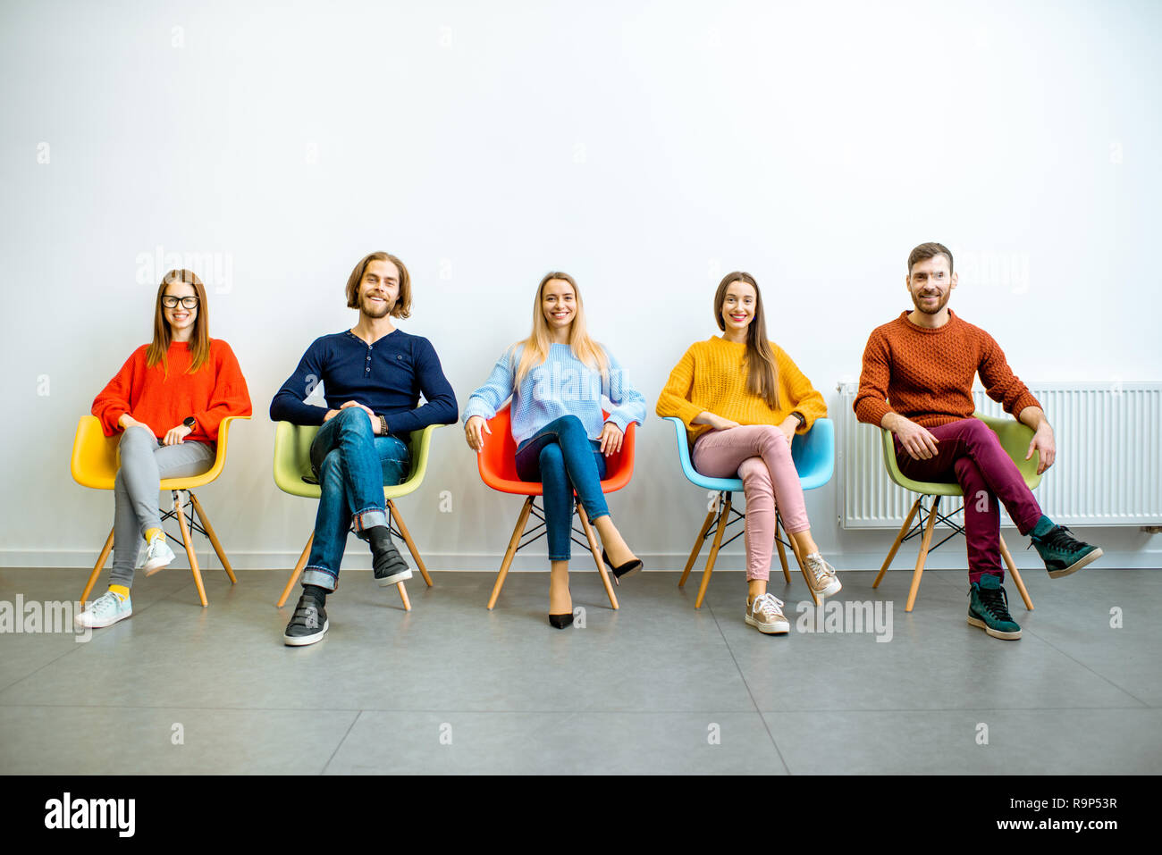 Portrait of a young people dressed casually sitting in a row on the ...