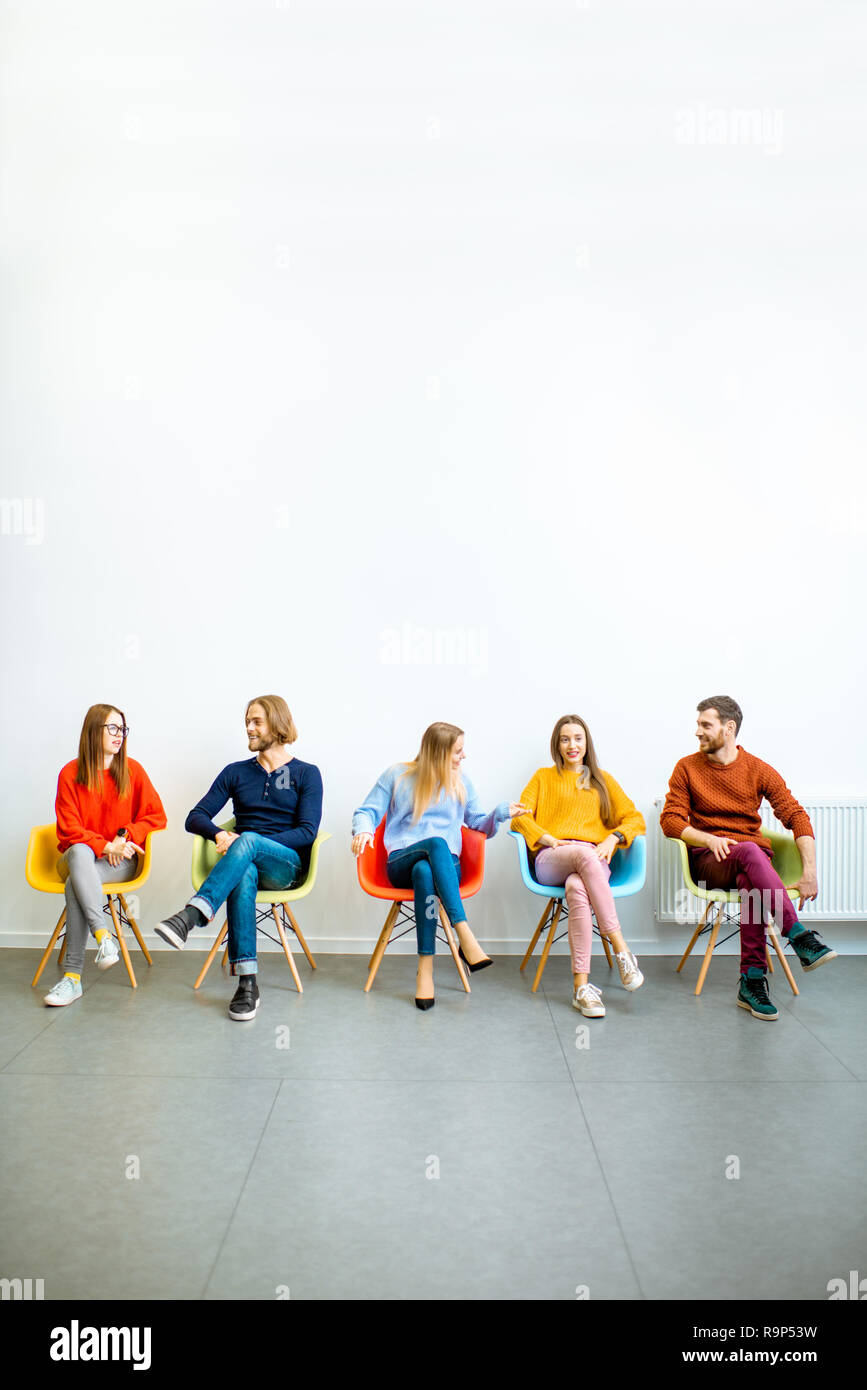 Portrait of a young people dressed casually sitting in a row on the ...