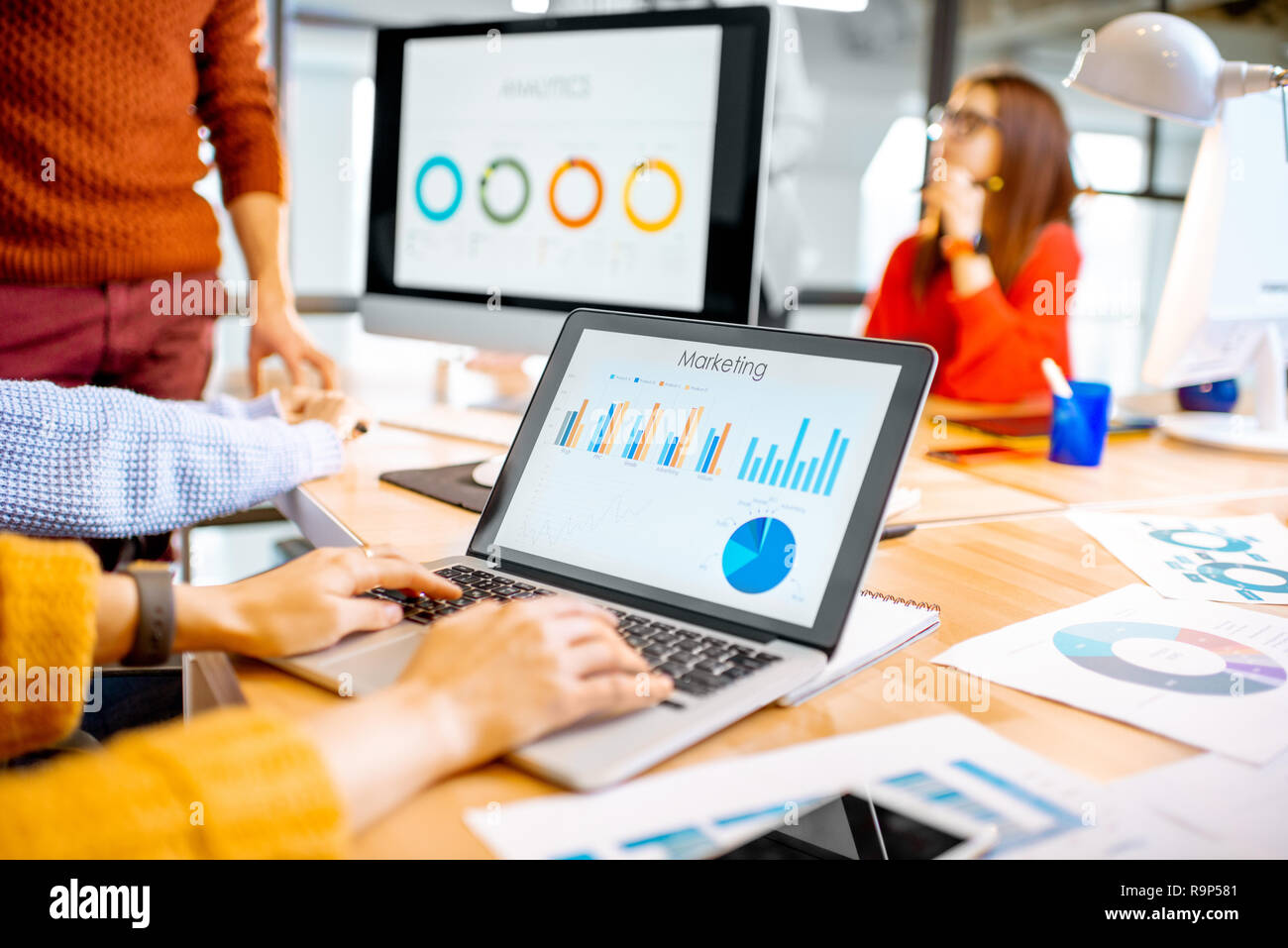 Group of young coworkers working on the computers with some charts in ...