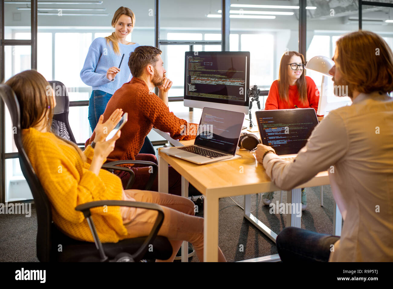 Team of a young programmers dressed casually working on computer code ...