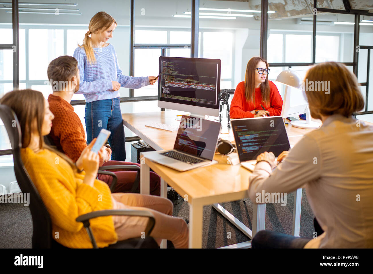 Team of a young programmers dressed casually working on computer code ...