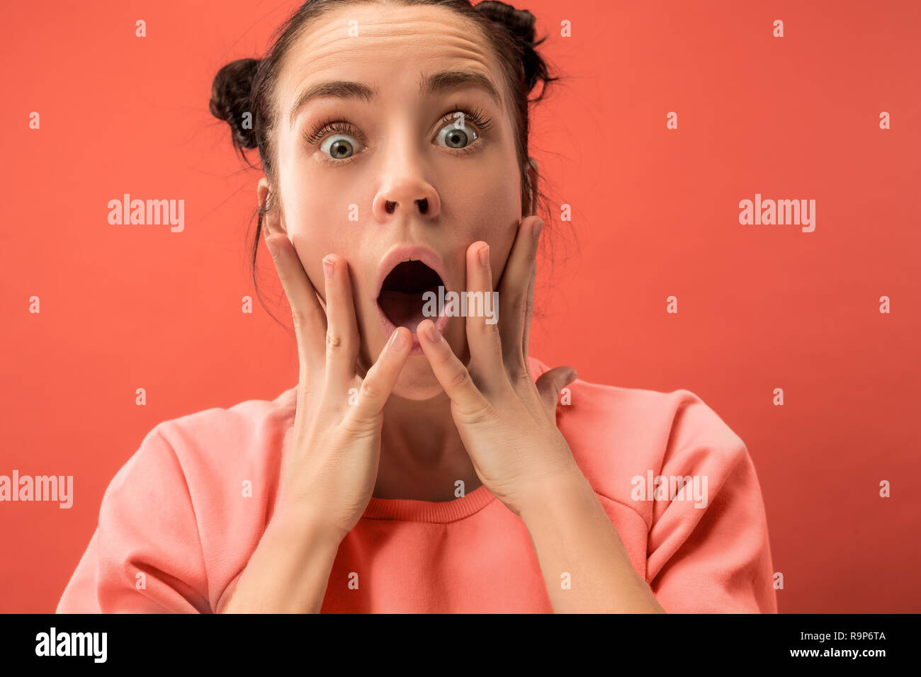 Delight. Beautiful female half-length front portrait isolated on coral ...