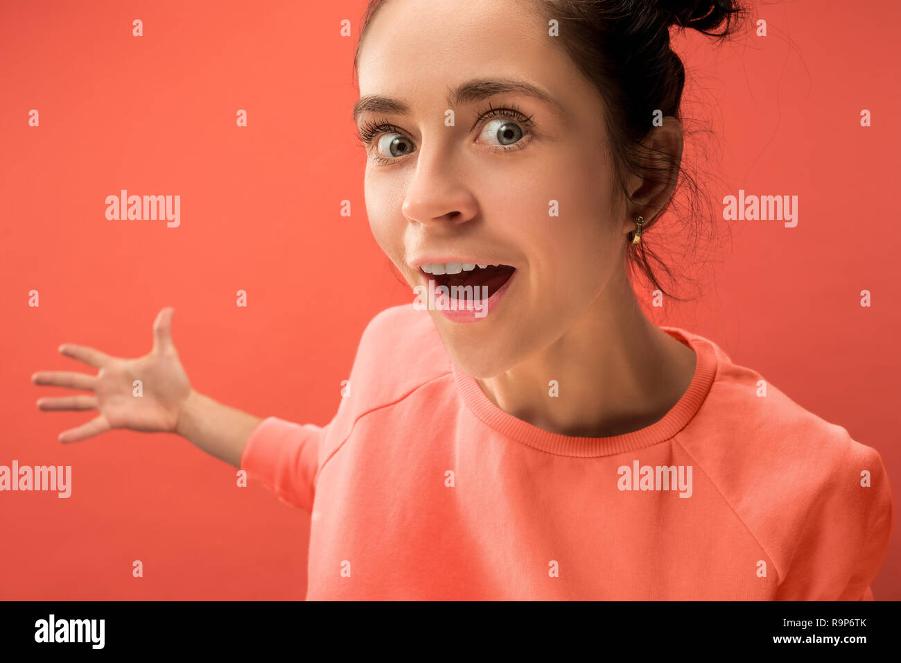 Delight. Beautiful female half-length front portrait isolated on coral ...