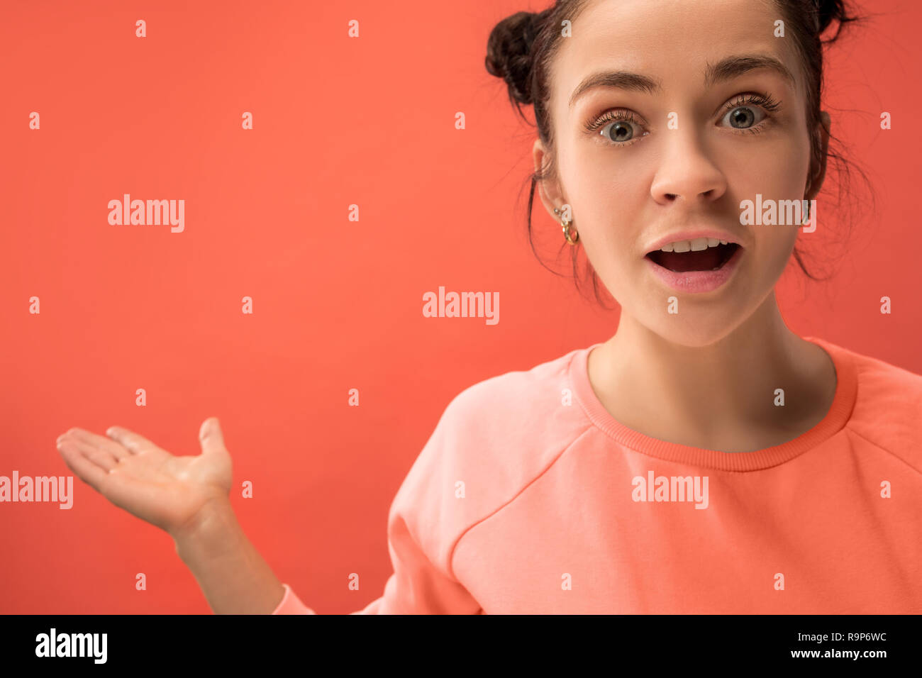 Delight. Beautiful female half-length front portrait isolated on coral ...