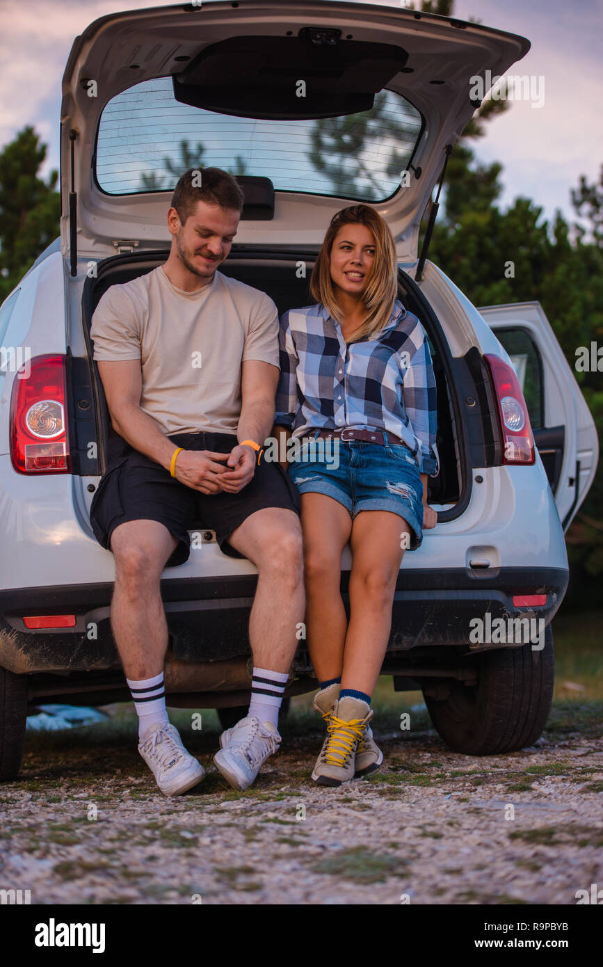 Young couple sitting on the back of a off road vehicle and enjoying the ...