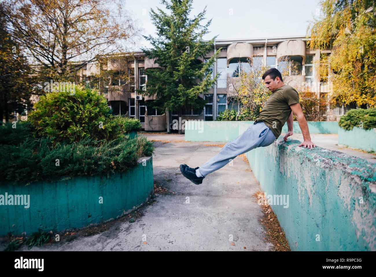 Young parkour guy jumping over a concrete wall and landing on another ...
