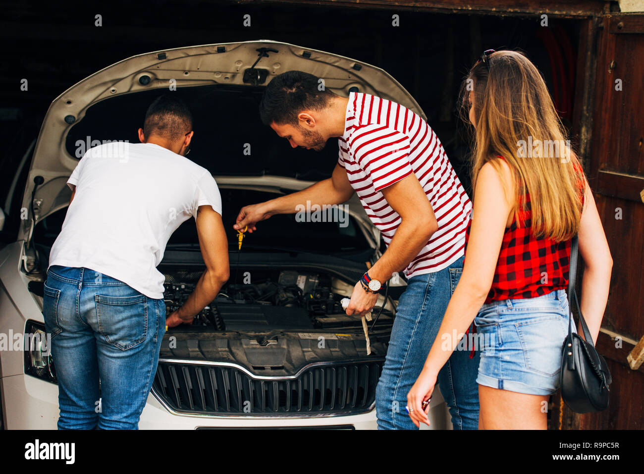 Three friends checking motor oil on car engine Stock Photo - Alamy