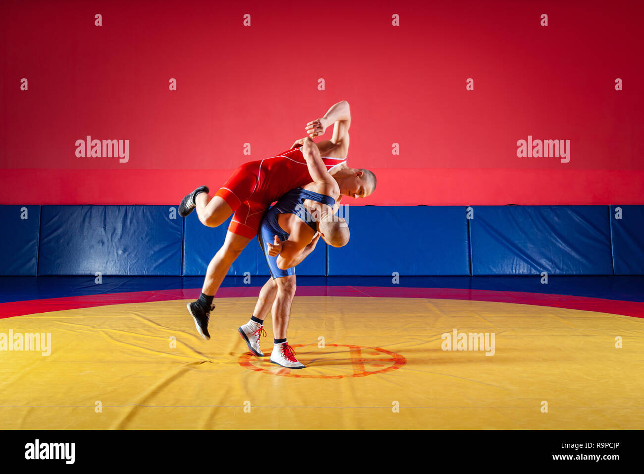 Two young men in blue and red wrestling tights are wrestlng and making ...