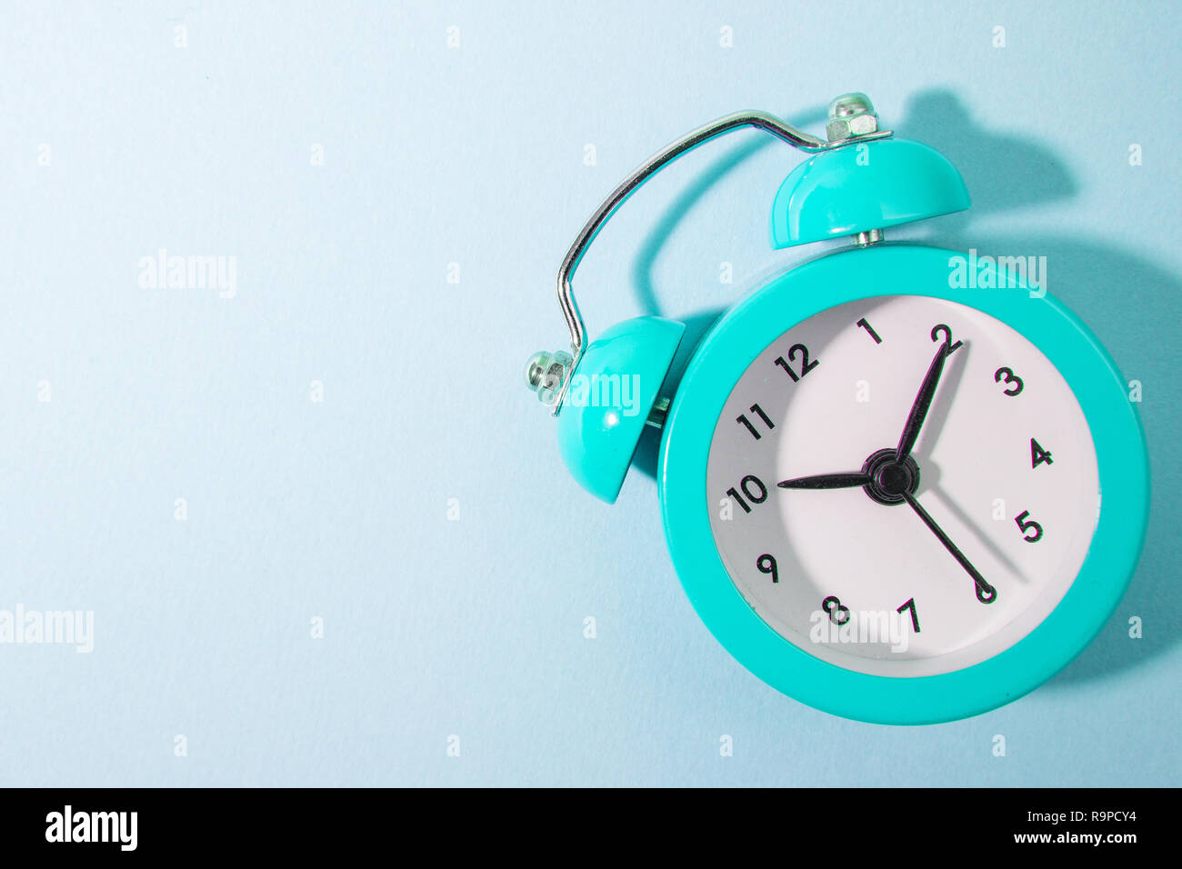 Blue background and blue alarm clock Stock Photo - Alamy