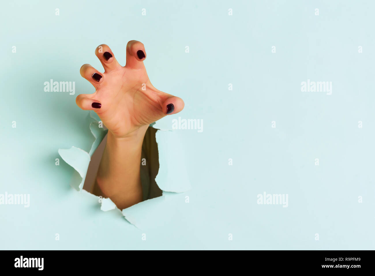 Female hand reaching through torn blue paper sheet Stock Photo - Alamy