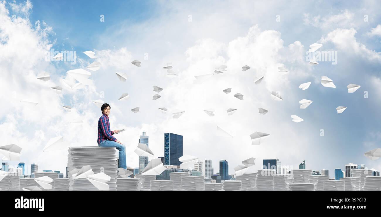 Attractive man sitting on pile of paper documents Stock Photo - Alamy