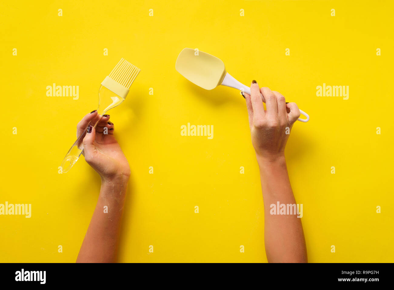 Woman hand holding kitchen utensils on yellow background. Baking tools ...
