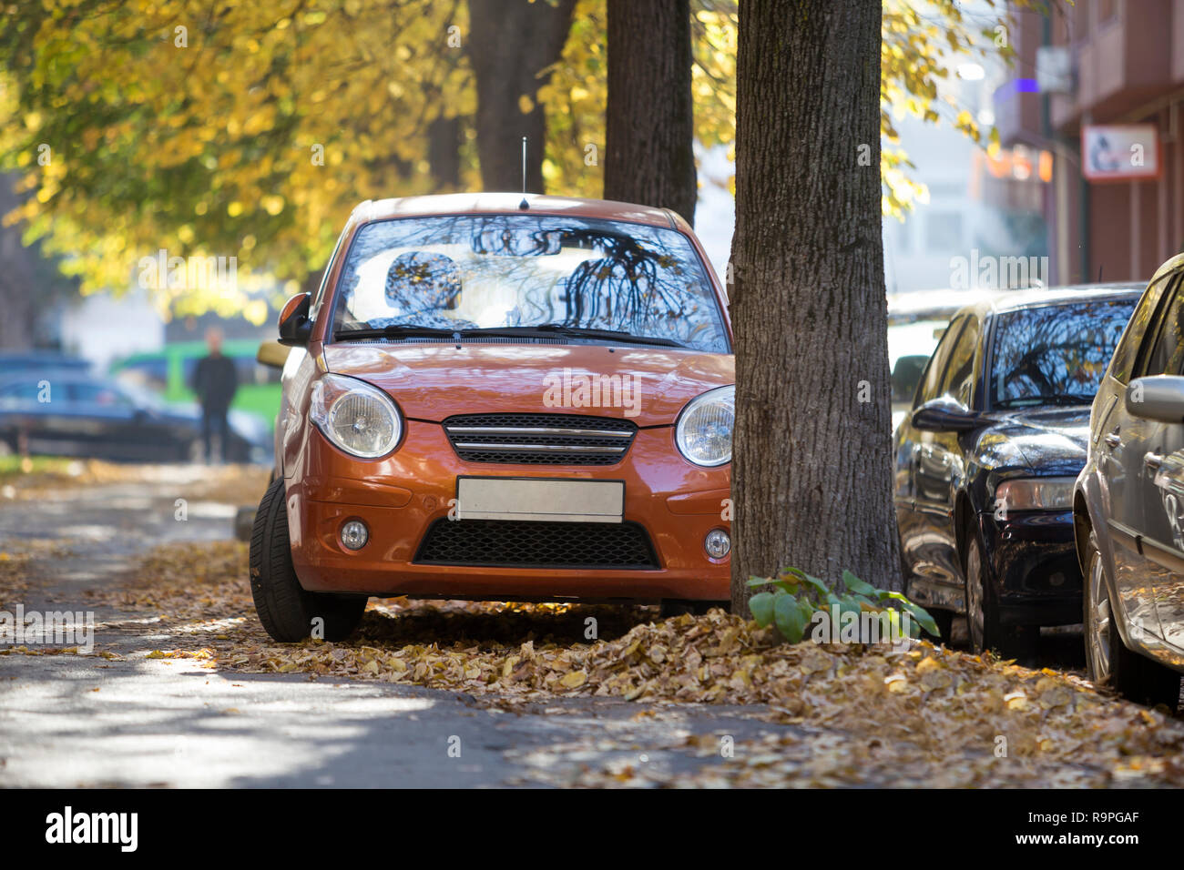 Front view of small orange mini car parked in quiet yard on sunny ...