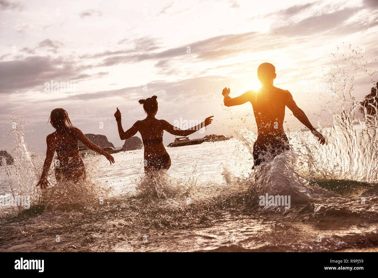 Group of happy friends run and jump at sunset sea beach. Tropical ...