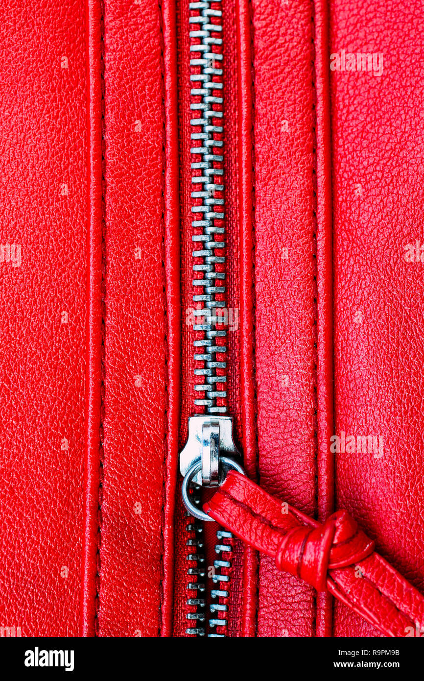 Zipper partly open close up detail macro photo on a red leather texture ...