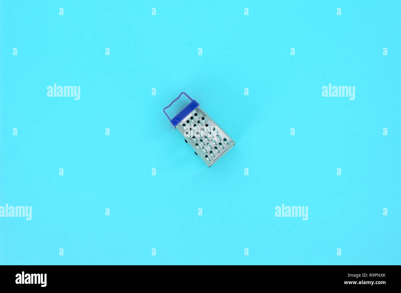 Stainless steel grater lies on a pastel colored paper. Kitchen ...