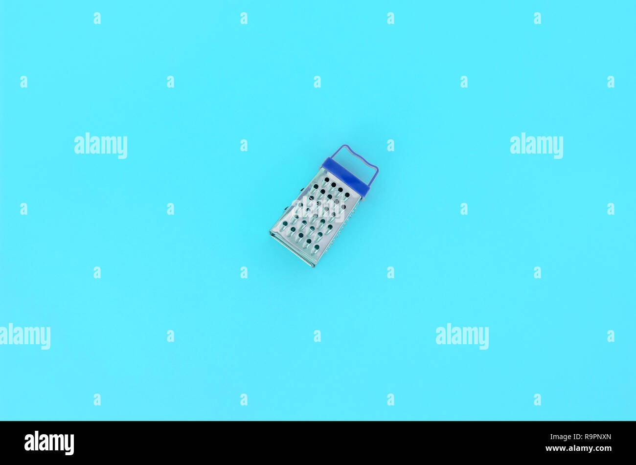Stainless steel grater lies on a pastel colored paper. Kitchen ...