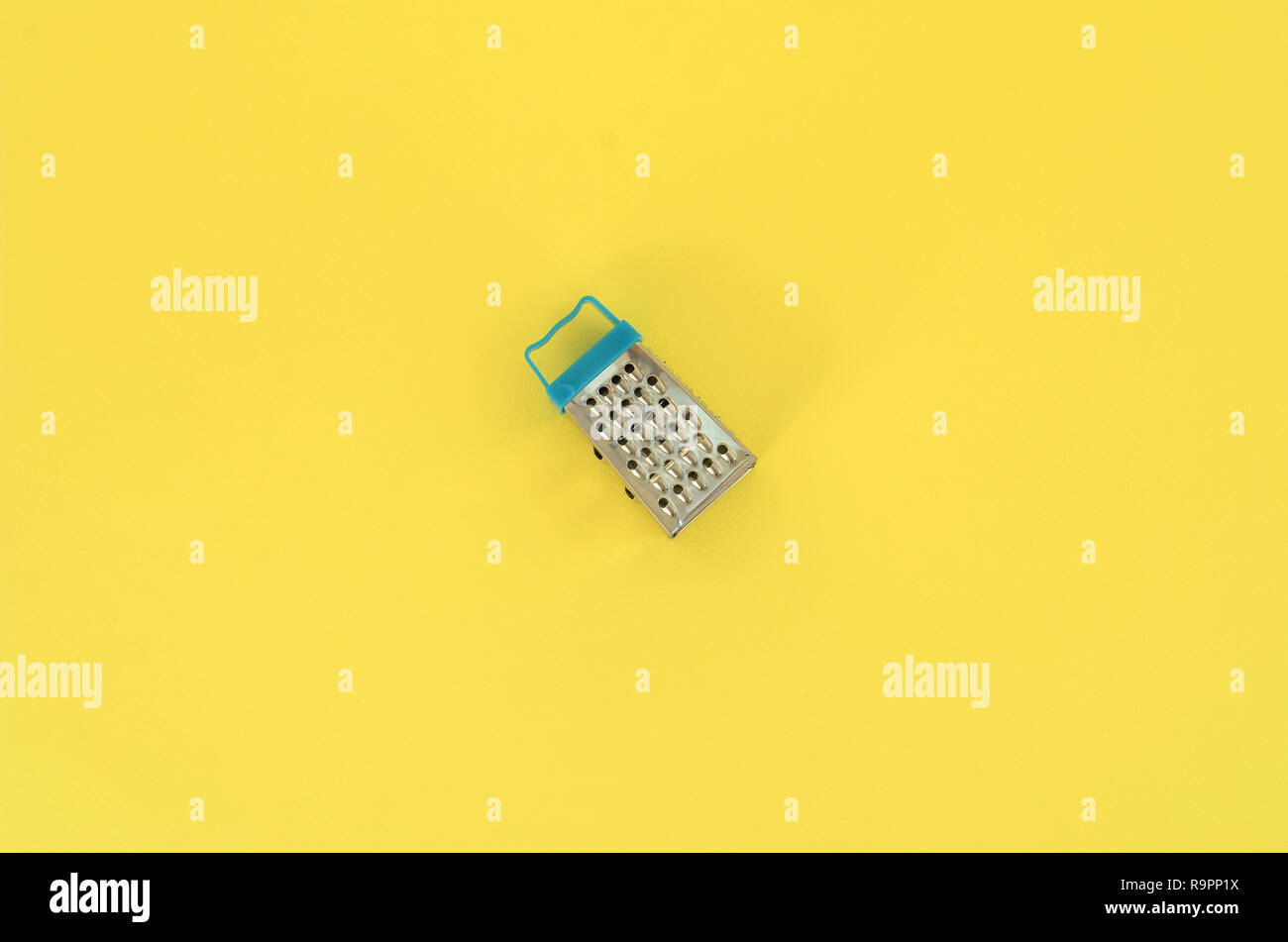 Stainless steel grater lies on a pastel colored paper. Kitchen ...