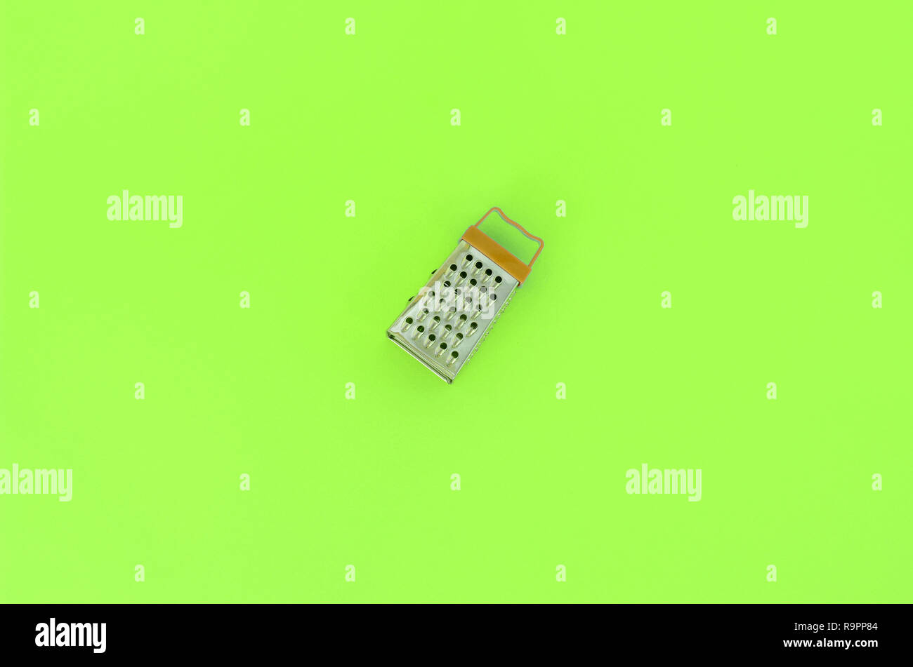 Stainless steel grater lies on a pastel colored paper. Kitchen ...