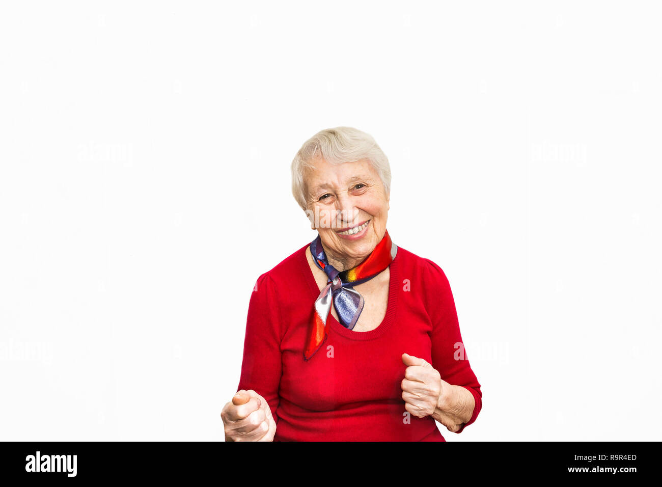 Old smiling woman with surprised expression on her face on red studio ...
