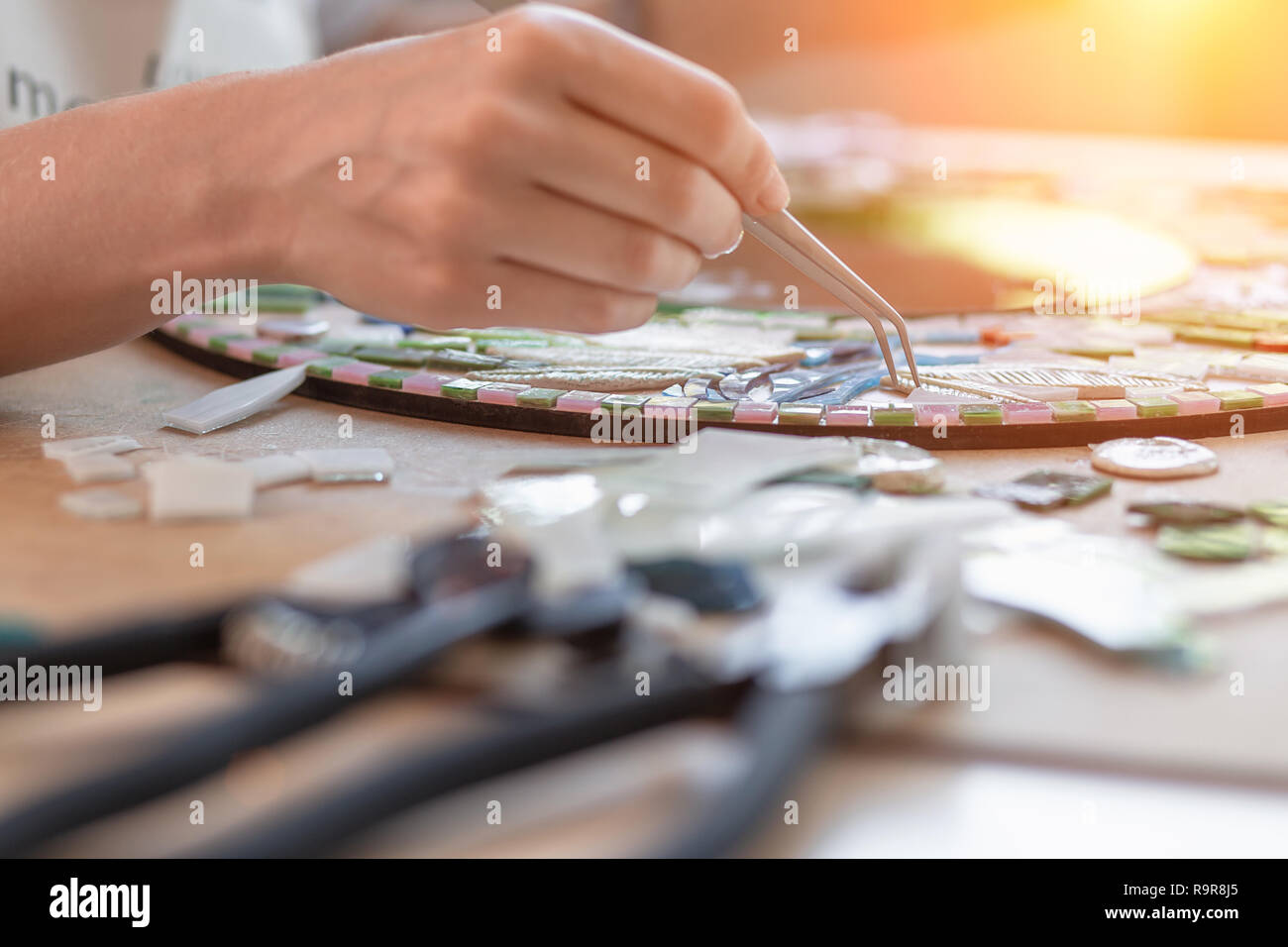 Hands of master working on new modern colorful mosaic. Close-up ...