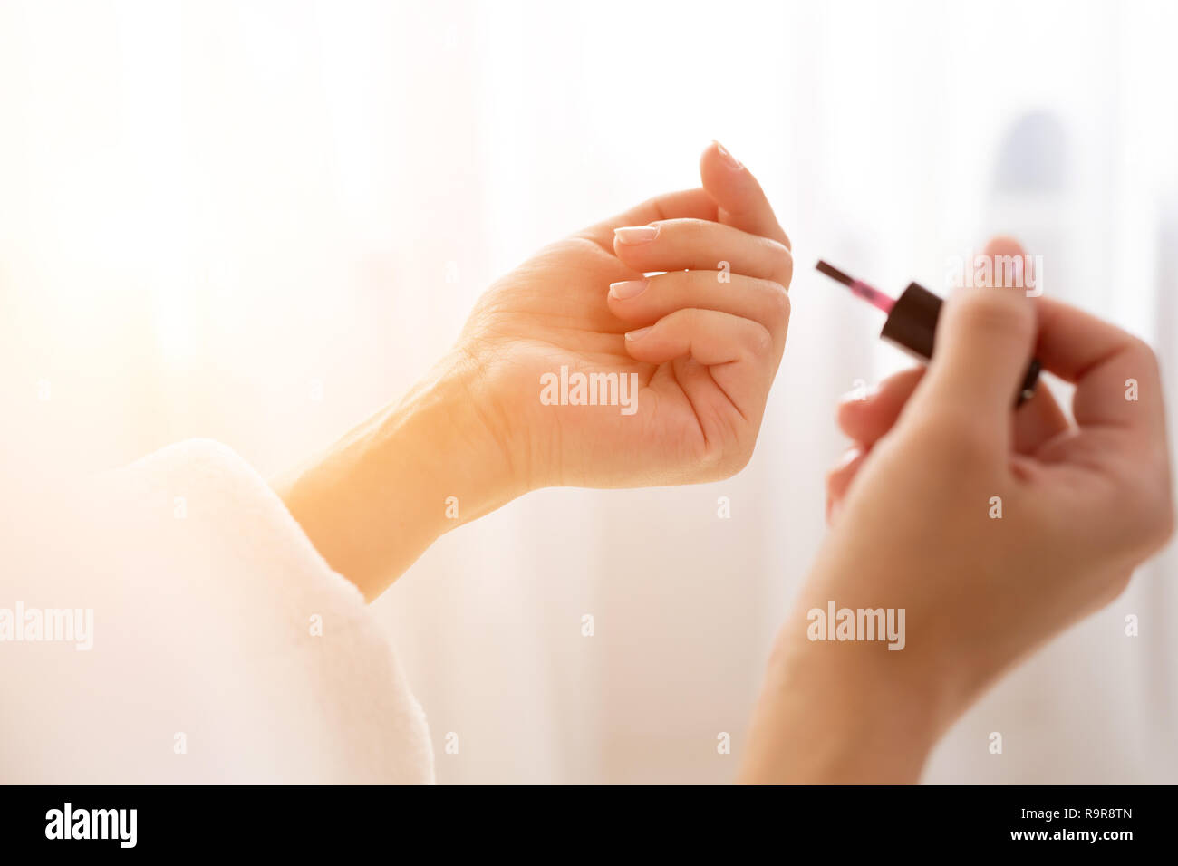 Close up of a shapely woman painted her nails in the morning, while ...