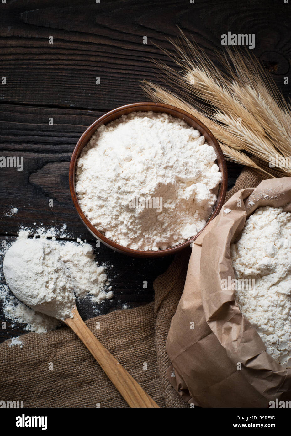 Flour in a wooden bowl, paper bag and spoon. Top view, space for text ...