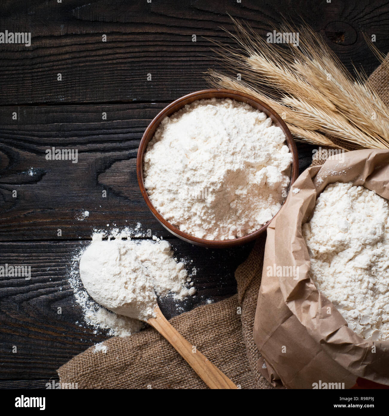 Flour in a wooden bowl, paper bag and spoon. Top view, space for text ...