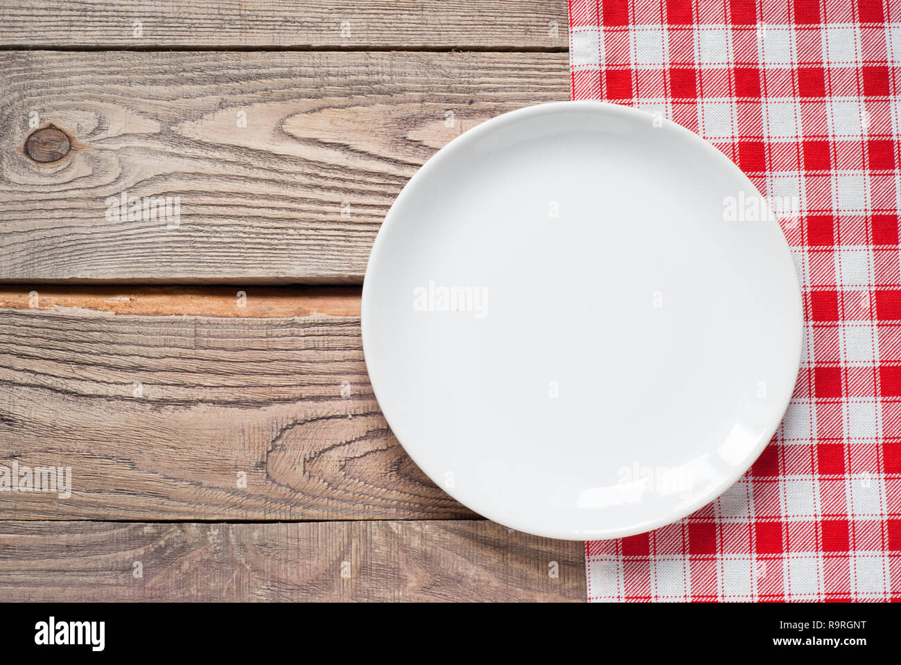 Empty white plate at wooden table. View from above with copy space ...