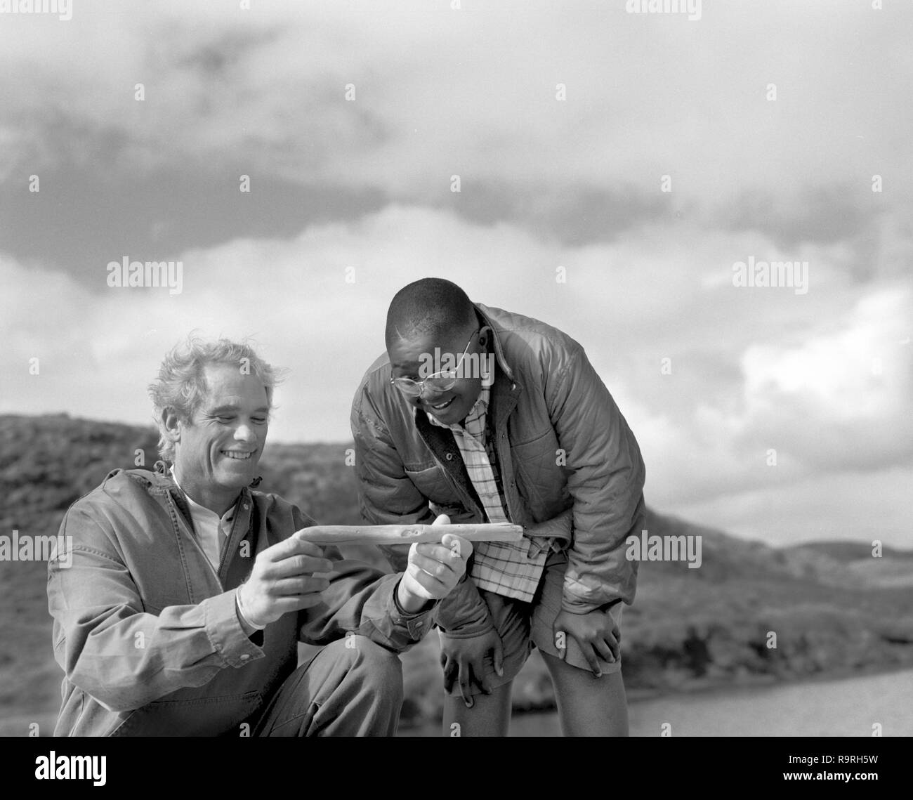 Man showing teenage boy a piece of drift wood Stock Photo - Alamy