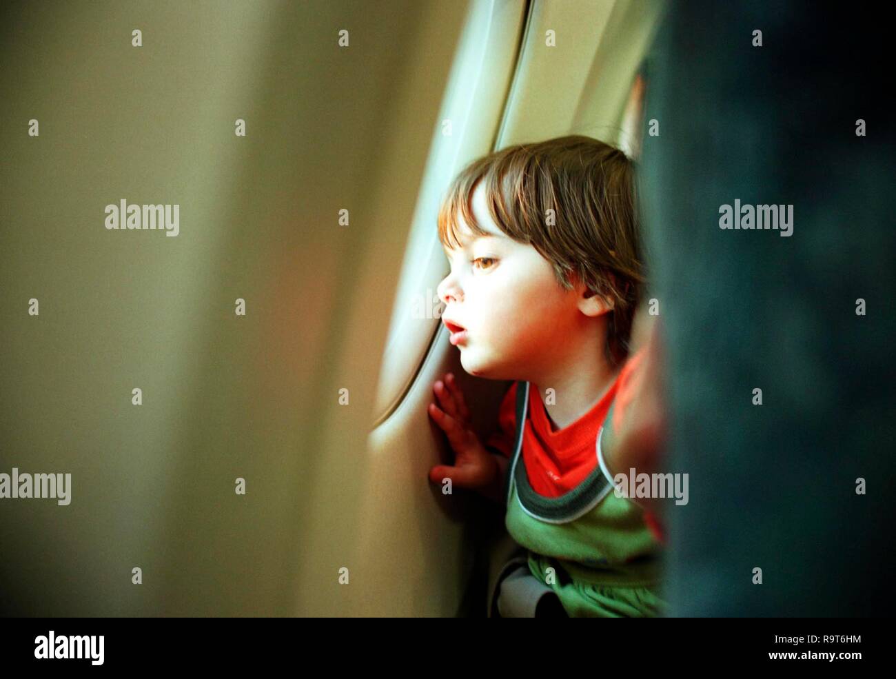 Child looking out airplane window while flying over Europe and USA ...