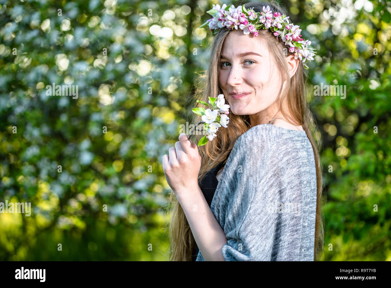 Happy young woman with spring blossom in the garden. Girl smelling ...