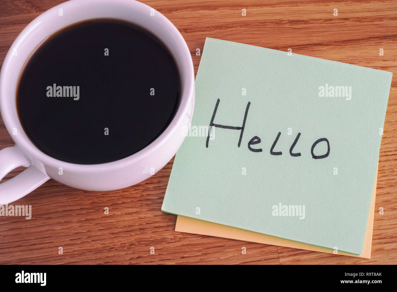 Hello. Post it note with writing Hello and cup of coffee. Close up ...