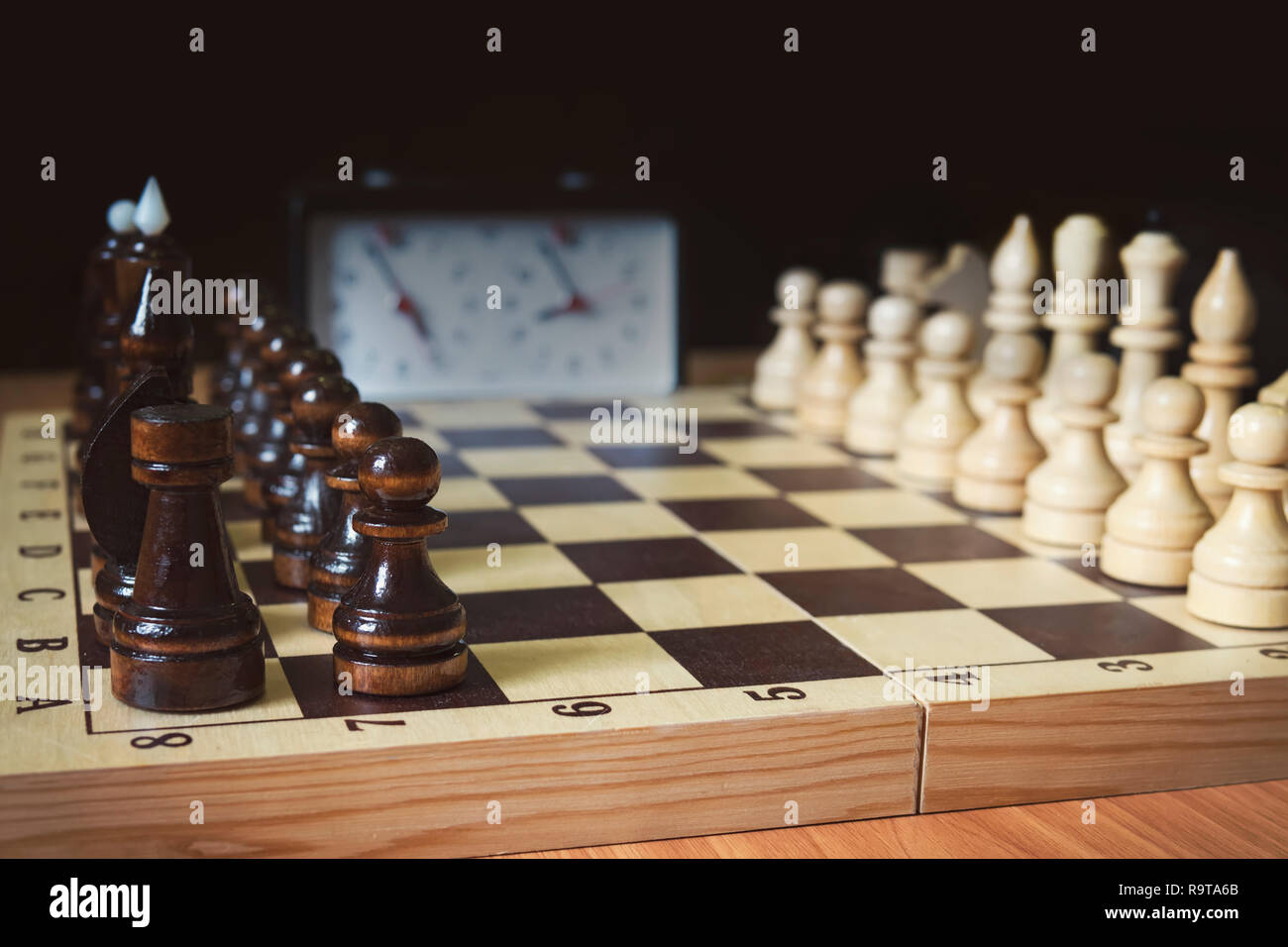 Chess background with a wooden board, chess pieces and clock close-up ...