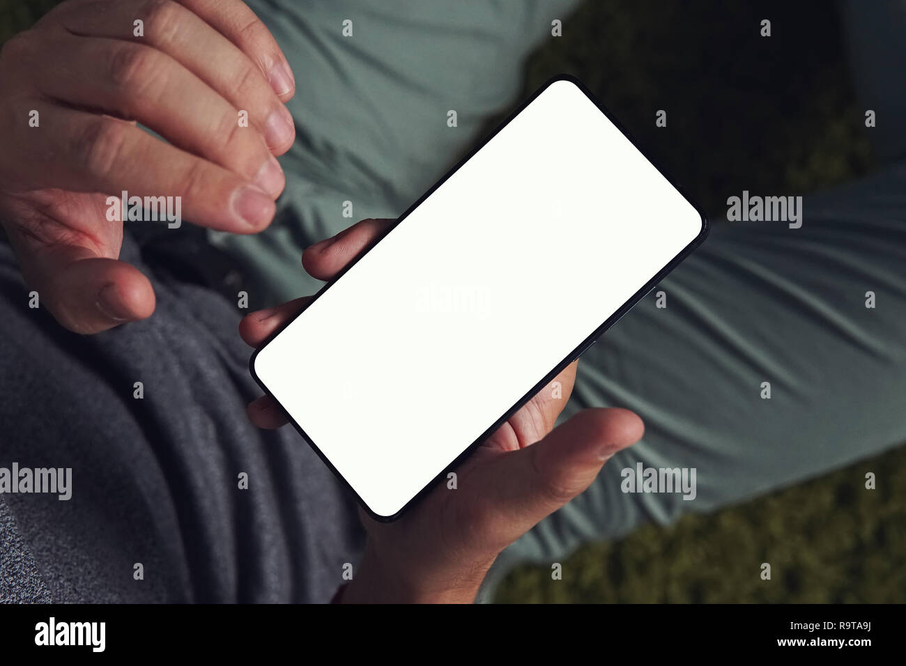A slantwise top-down view of a young man using the smartphone with the ...