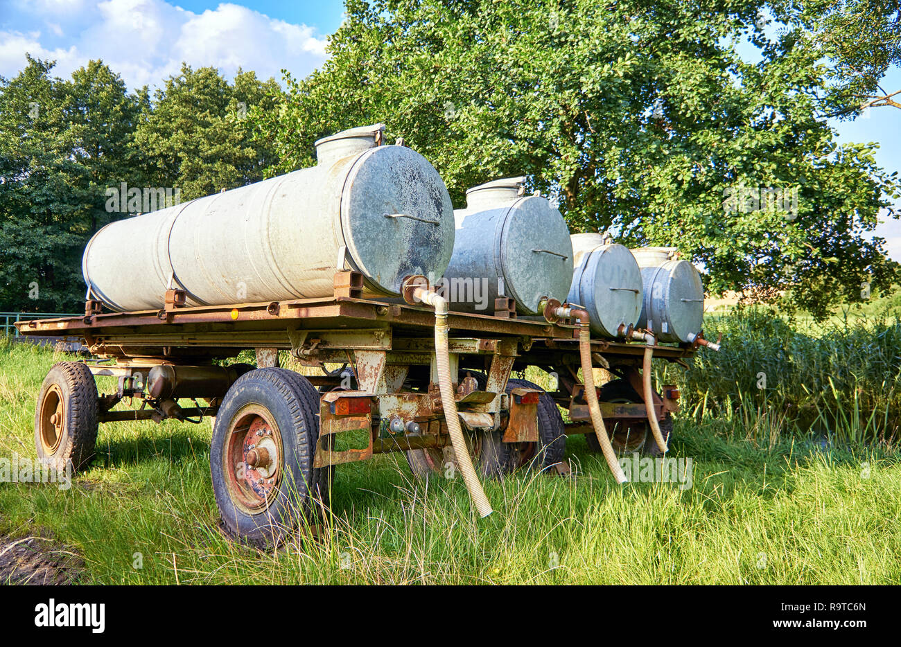 Four old metal water tanks on trailer for cattle on pasture Stock Photo ...
