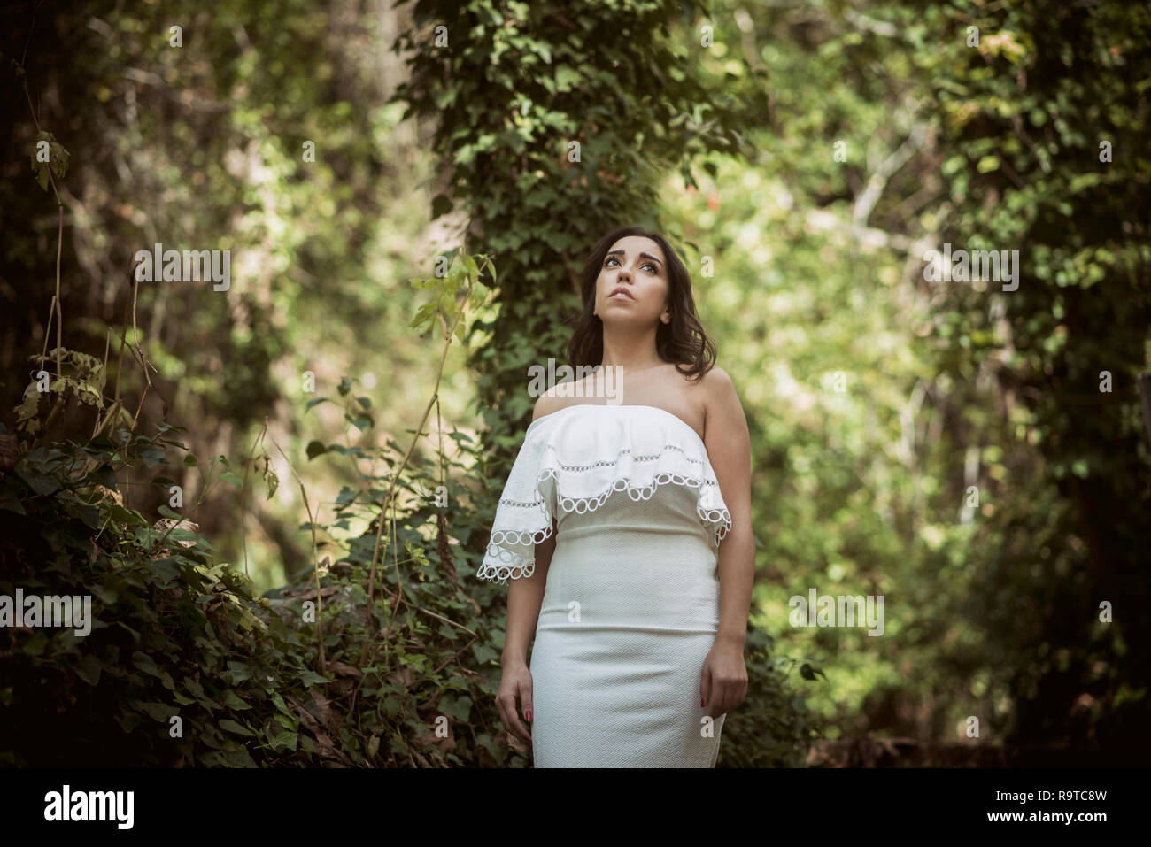 Worried young woman looking up in the woods Stock Photo - Alamy