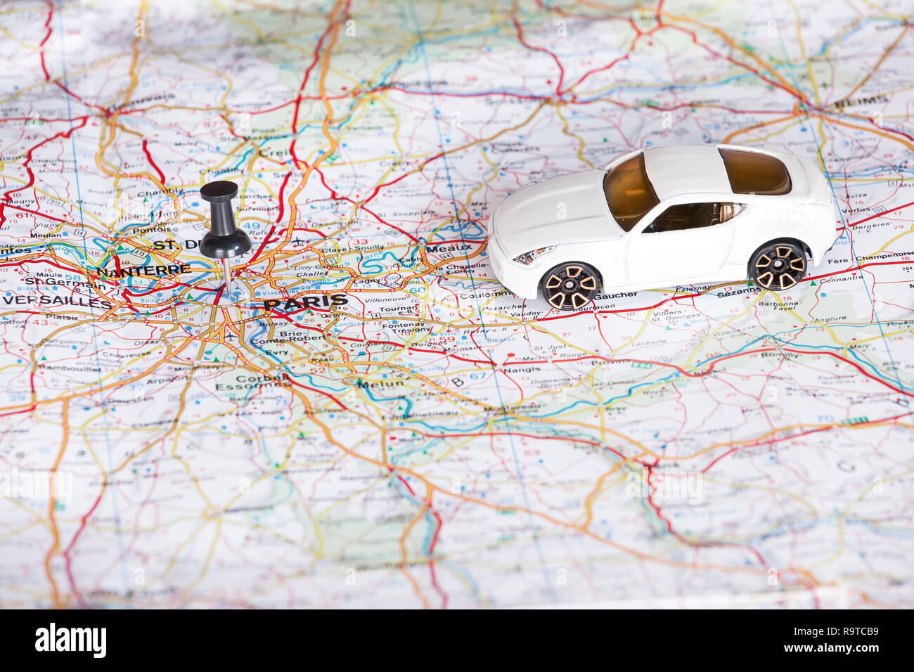 White toy car and a black pin on a map. Shallow depth of field. Concept ...