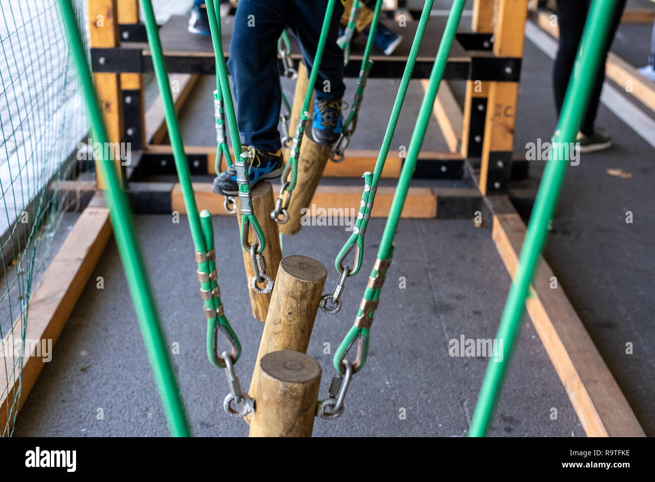 children walking on trunks suspended by ropes in an adventure park ...
