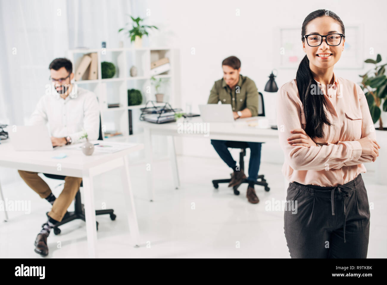 Selective focus of female office manager standing with crossed arms ...