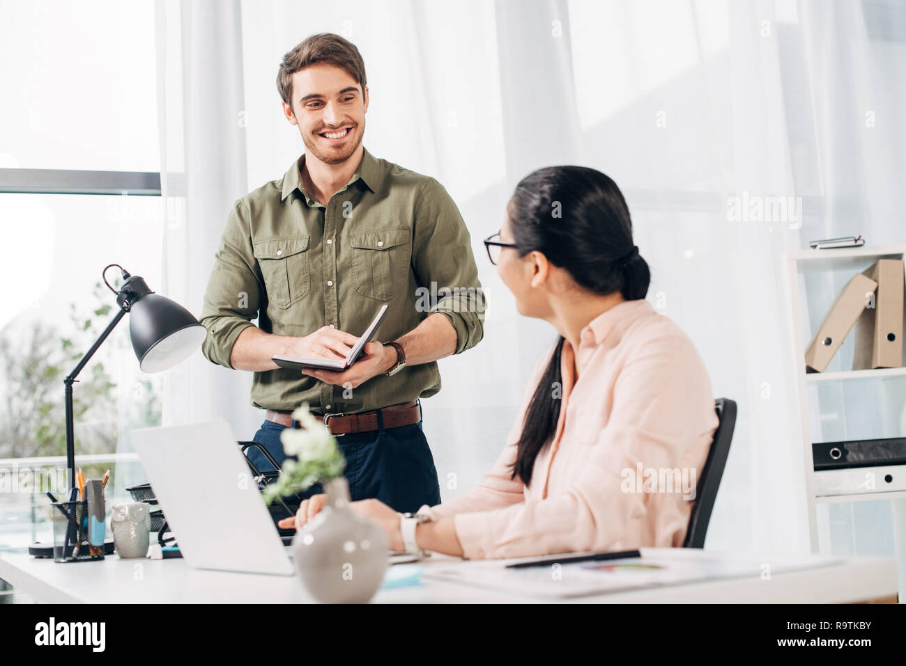 Male manager looking at female coworker in modern office Stock Photo ...