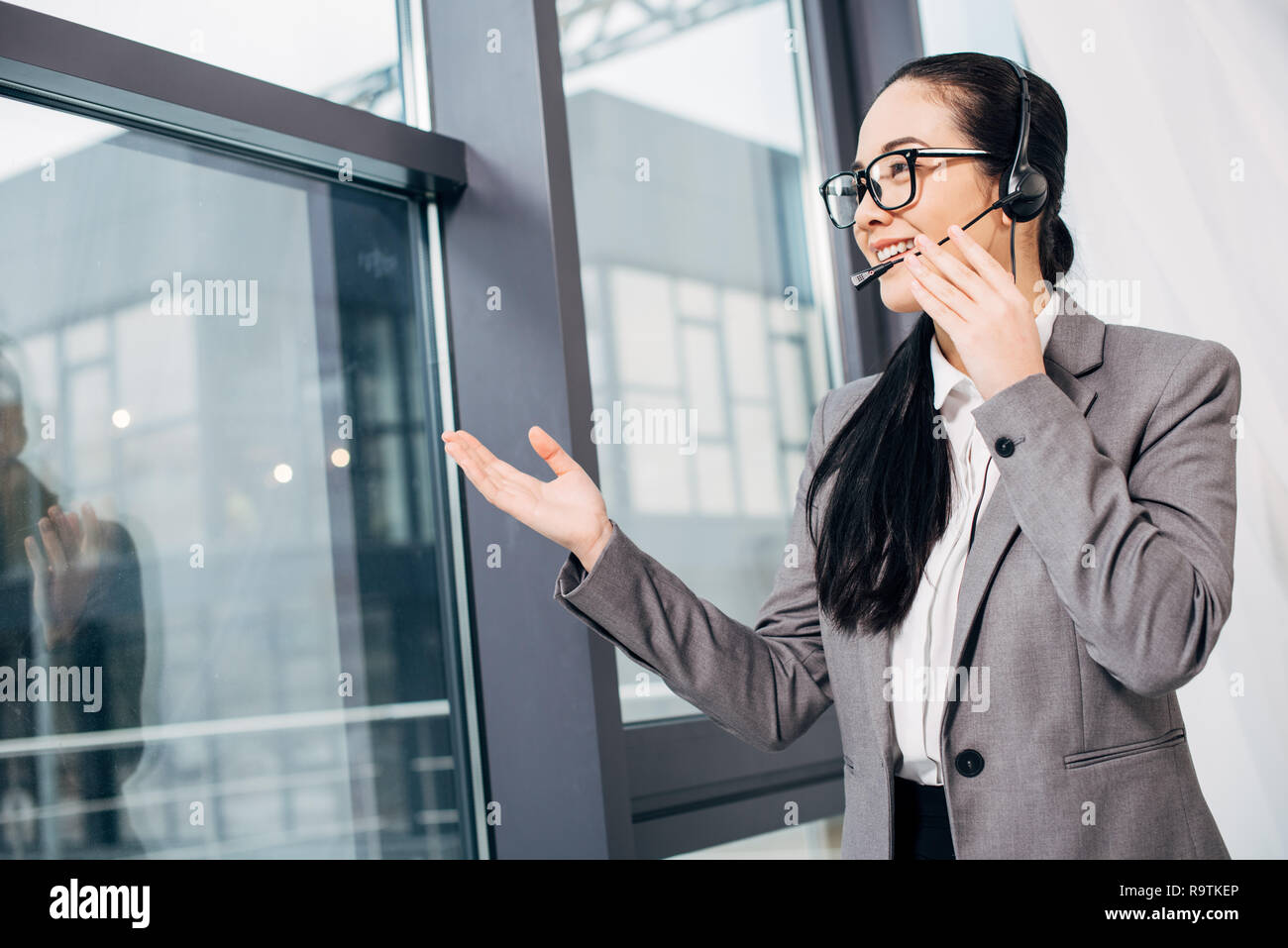 pretty call center operator touching headset and speaking in microphone ...
