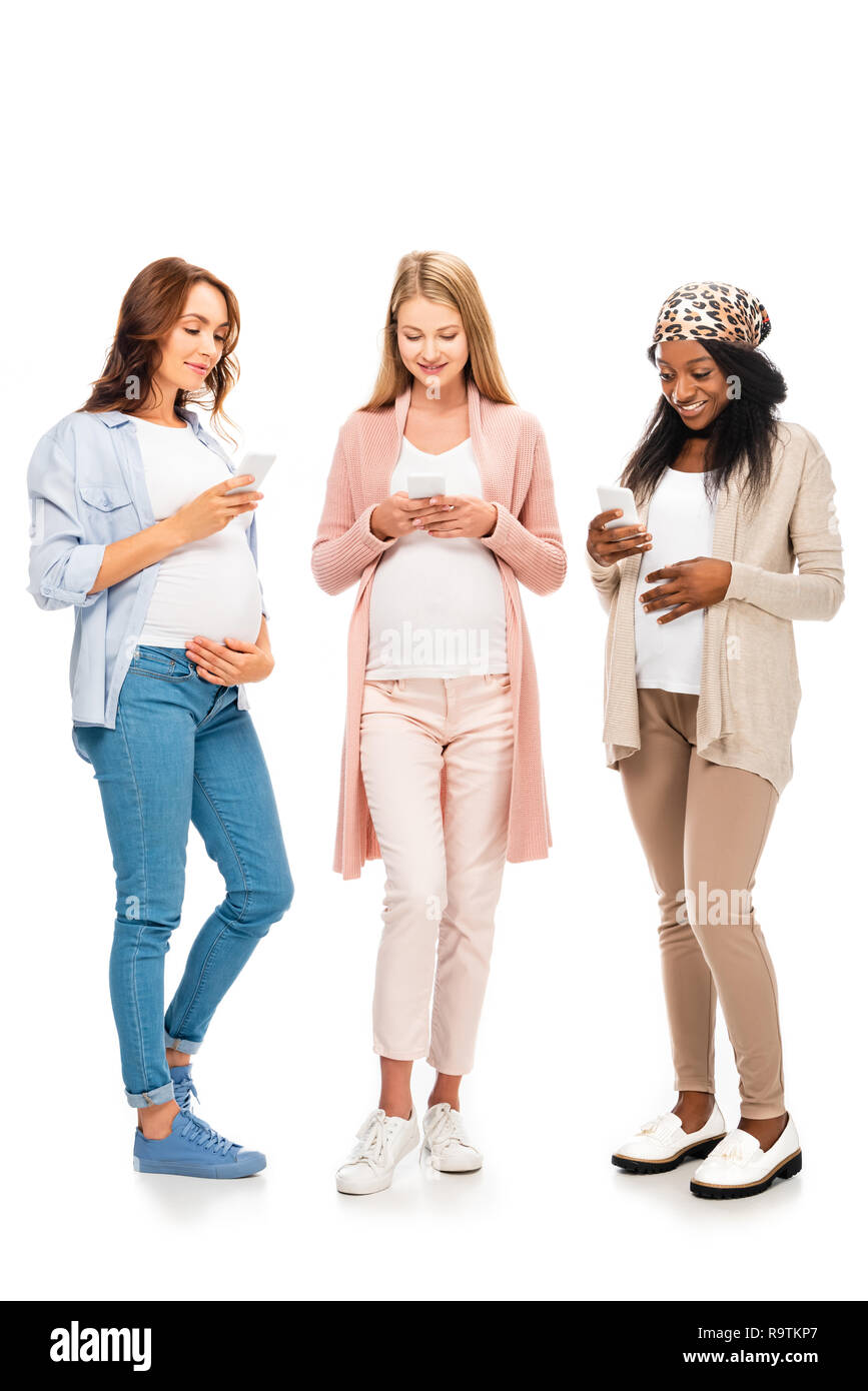 smiling multicultural pregnant women using smartphones isolated on ...