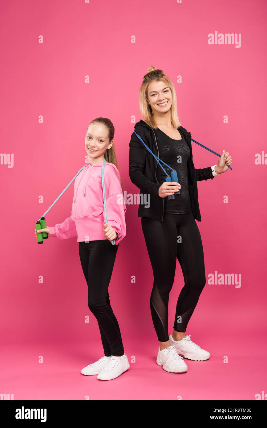 happy mother and daughter in sportswear holding skipping ropes ...