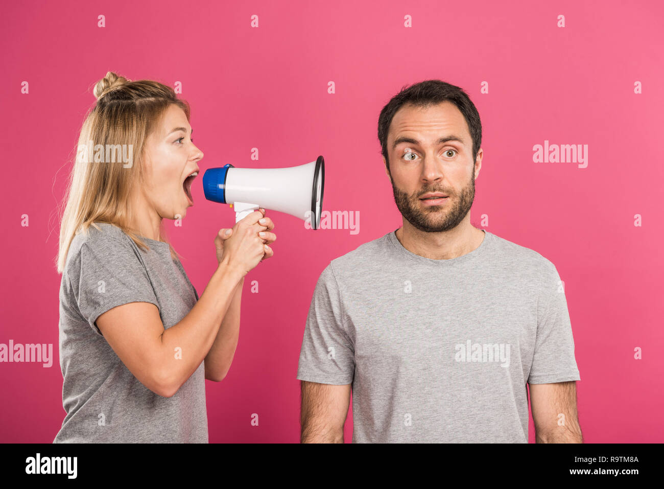 angry woman yelling with megaphone at man, isolated on pink Stock Photo ...