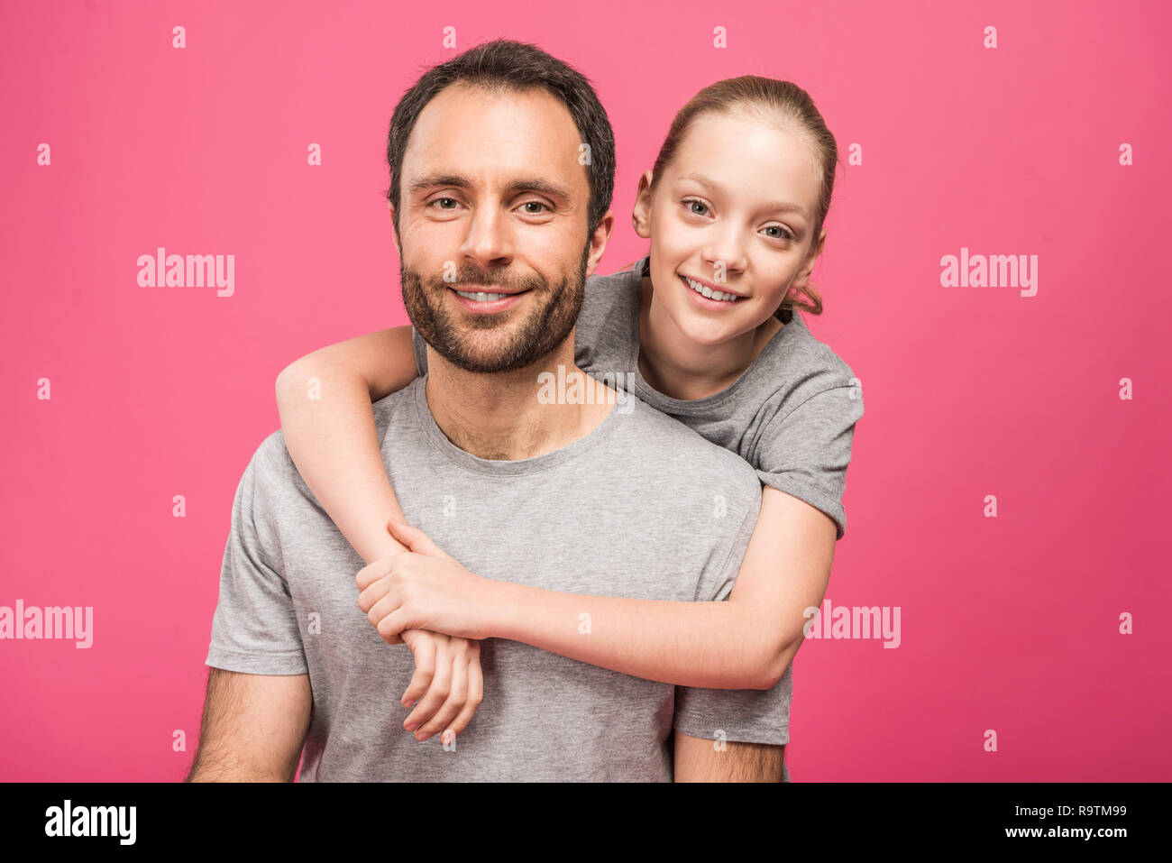 smiling blonde daughter hugging her father, isolated on pink Stock ...