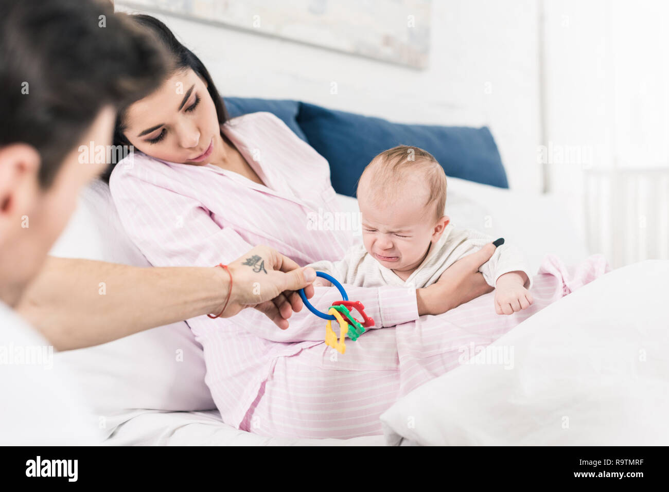 mother holding crying baby in hands with father near by at home Stock ...