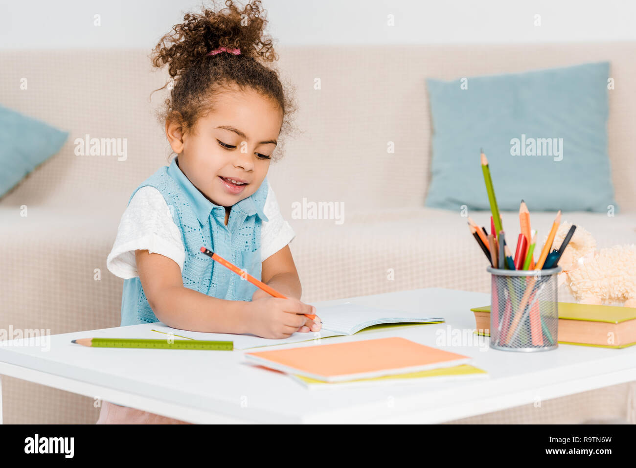 adorable smiling african american child studying and writing with ...