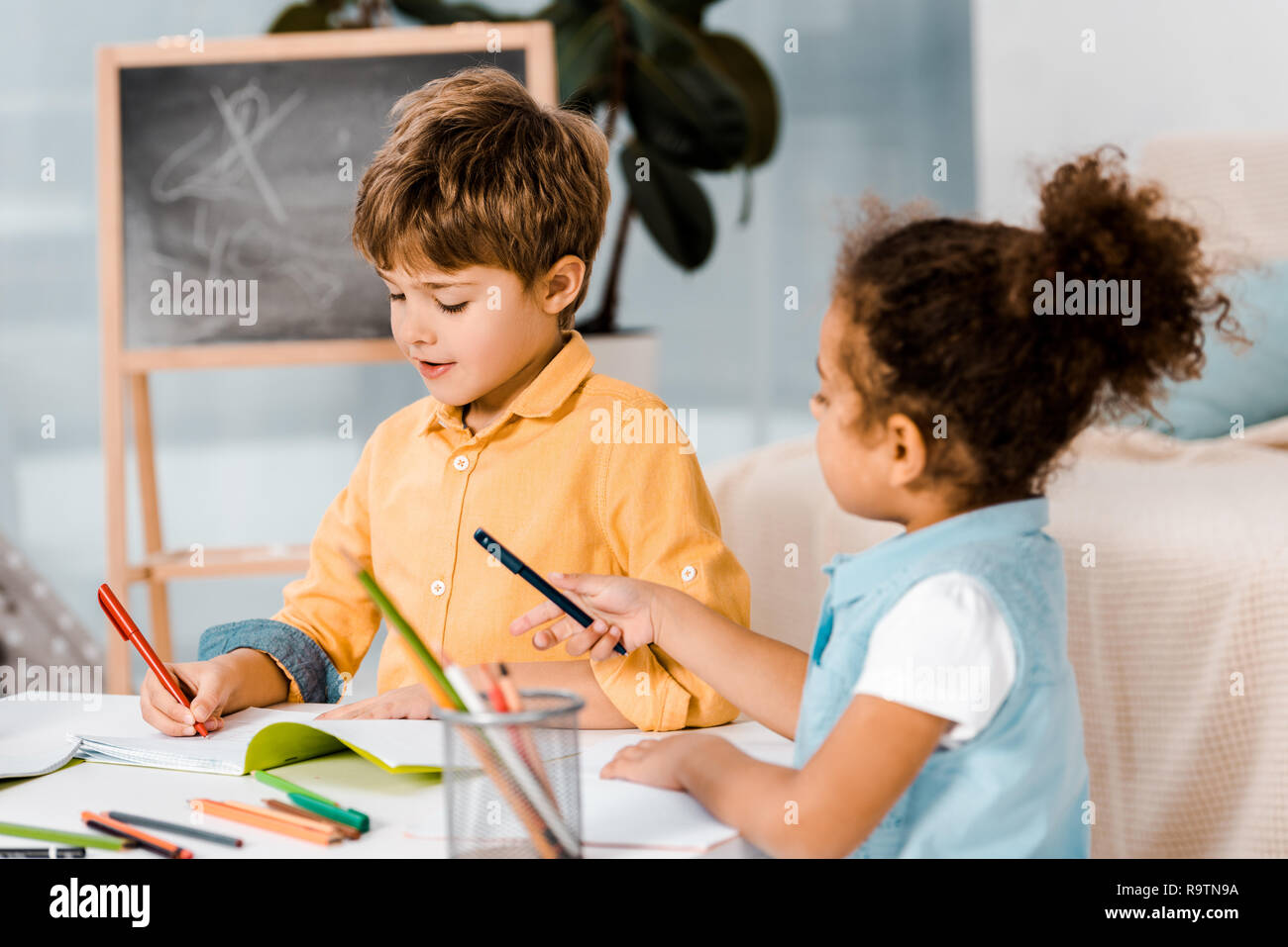 cute multiethnic children sitting and writing with pens together Stock ...